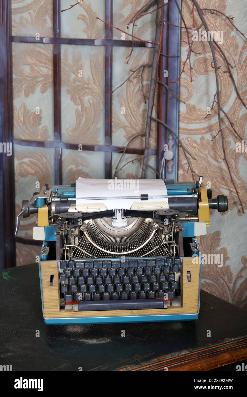 Old typewriter on desk with leather top and branch on wall in studio ...
