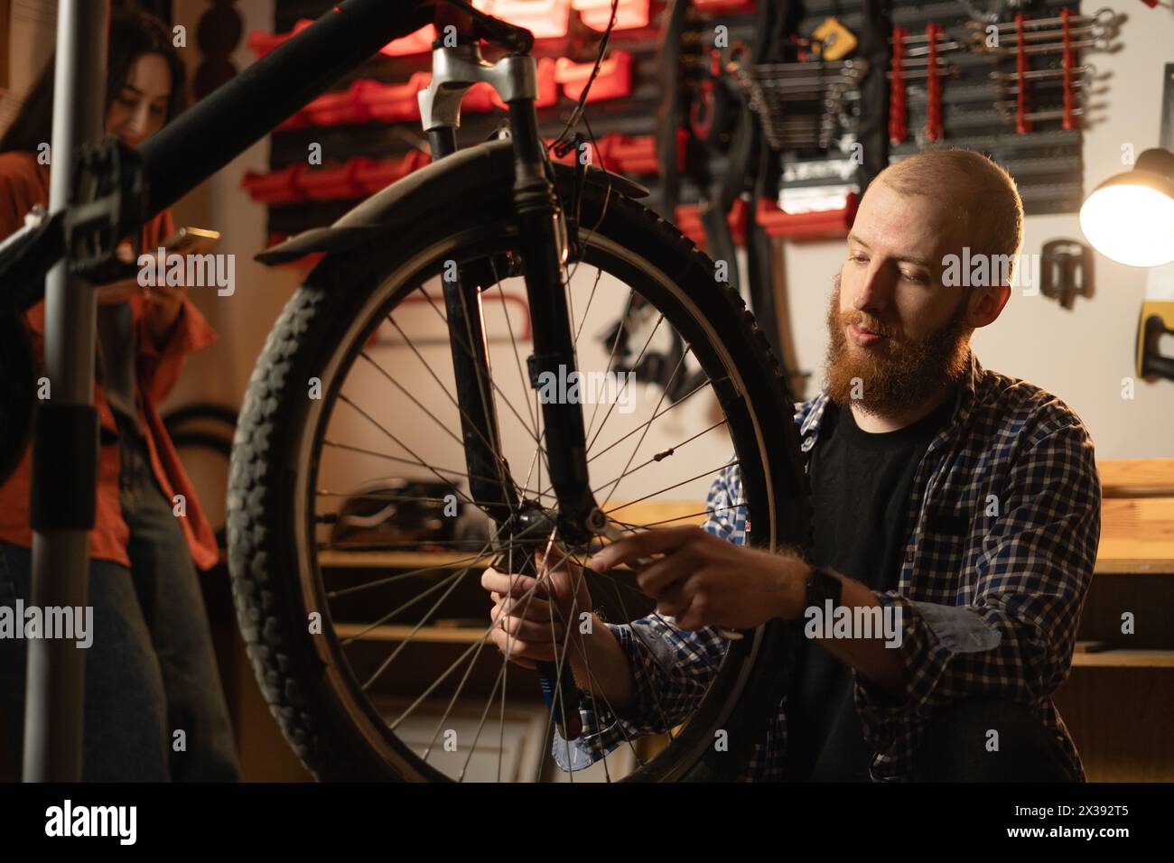 Young beard bicycle mechanic repairing bicycles in a workshop or garage ...