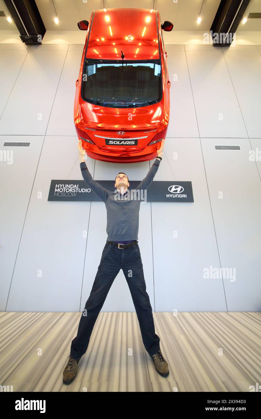 MOSCOW - APR 16, 2016: Red Hyundai Solaris on wall and man stands under ...