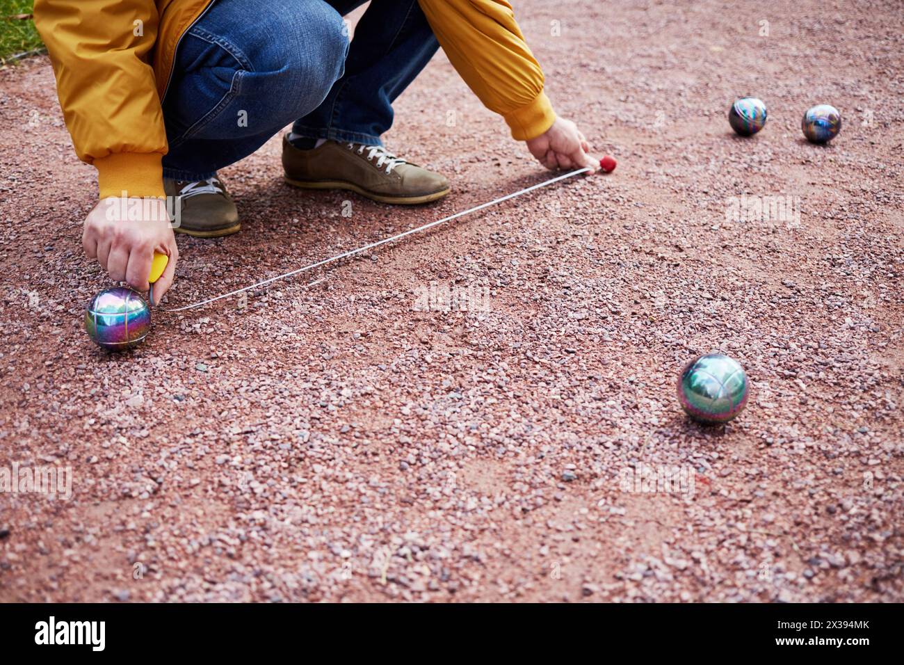 Man measures distance between balls during petanque game Stock Photo ...