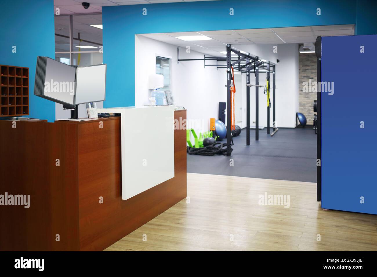 Empty stylish reception with wooden counter and blue walls in fitness ...