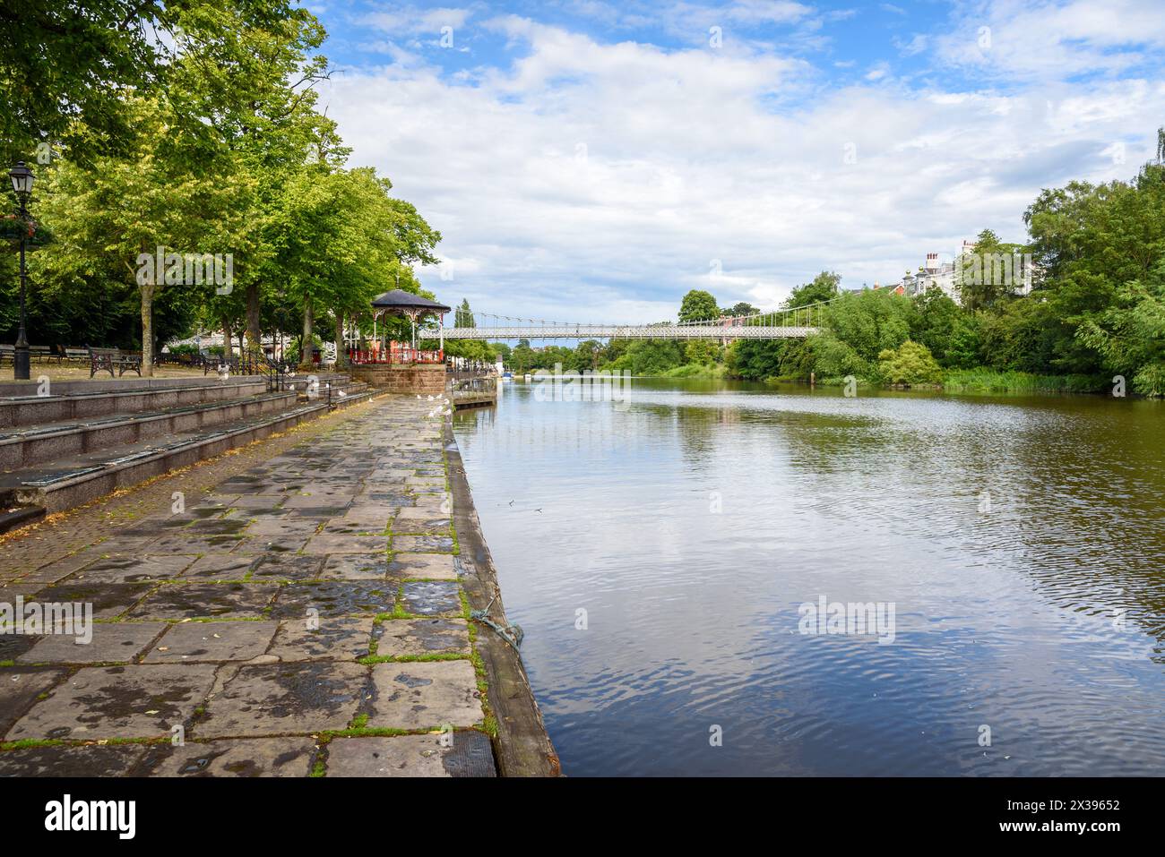 Empty riverbank stone footpath lined with trees and benches. An empty ...