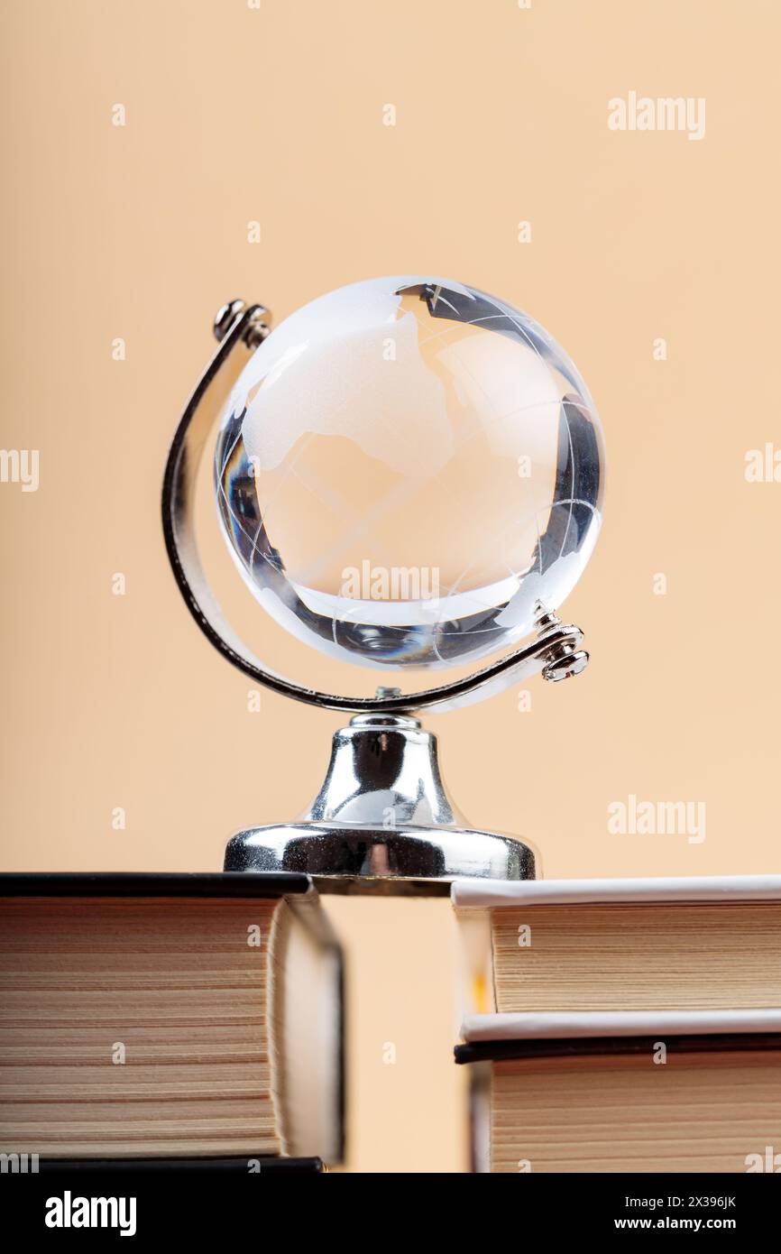 Glass Globe on Stack of Books on Beige Background, Fragile Balance of ...