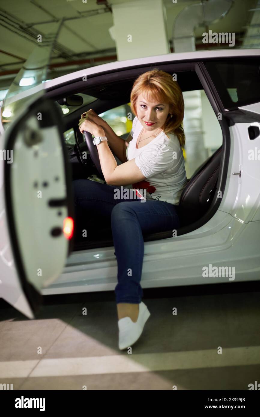 Smiling woman going to get out of car at underground parking Stock ...
