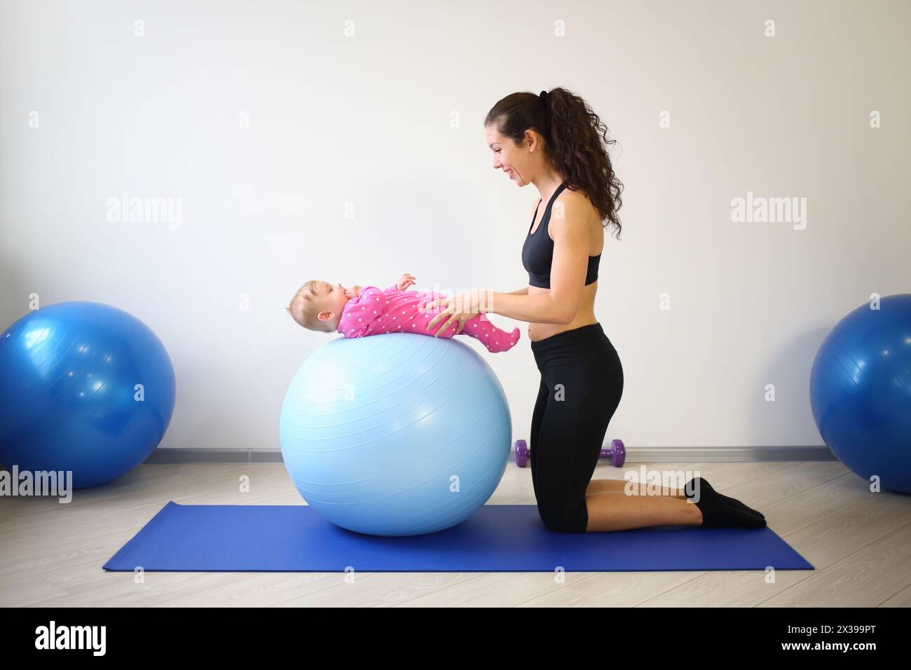 Mother doing gymnastics with a baby on fitball in gym Stock Photo - Alamy