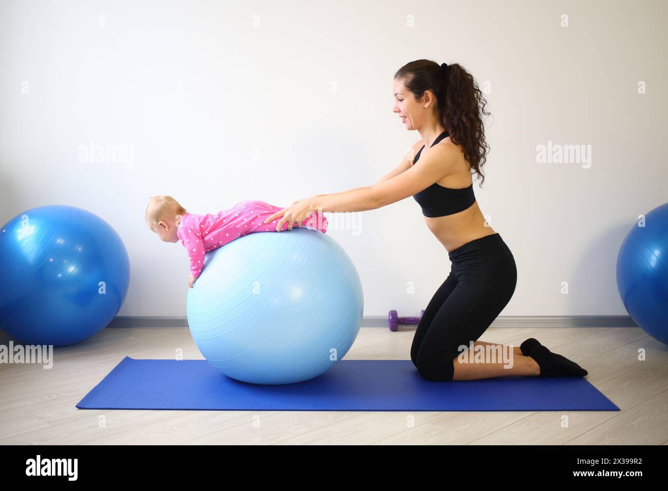 Mother and baby doing exercises on the big blue ball in the gym Stock Photo - Alamy