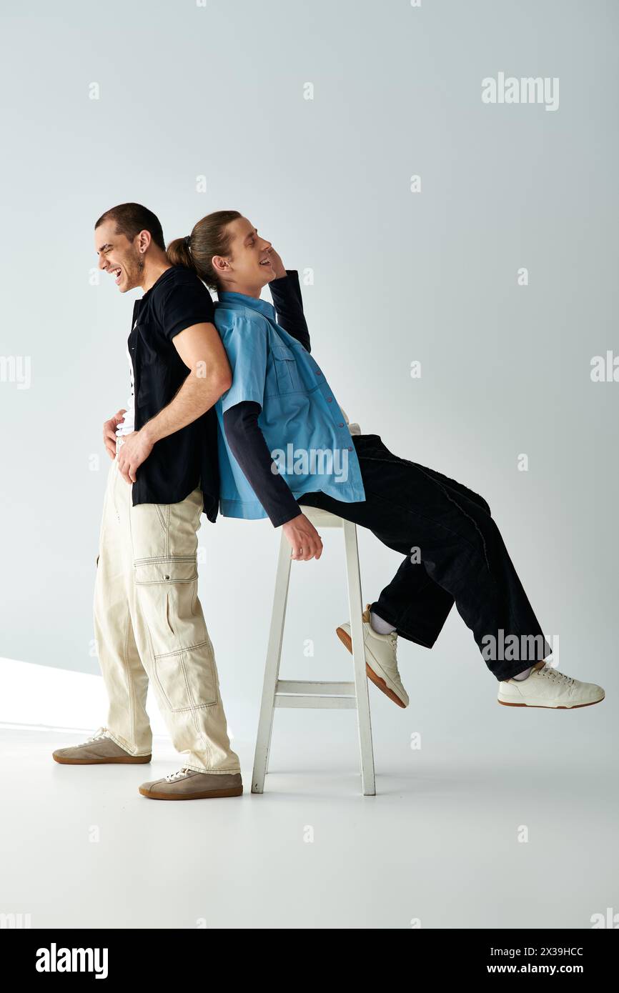 A man seated on a stool, another man standing beside him Stock Photo ...