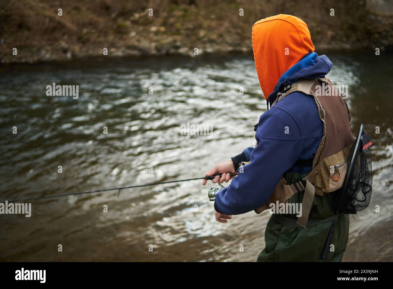 Fisherman fishing by the river in daytime with tackle bag and net Stock ...