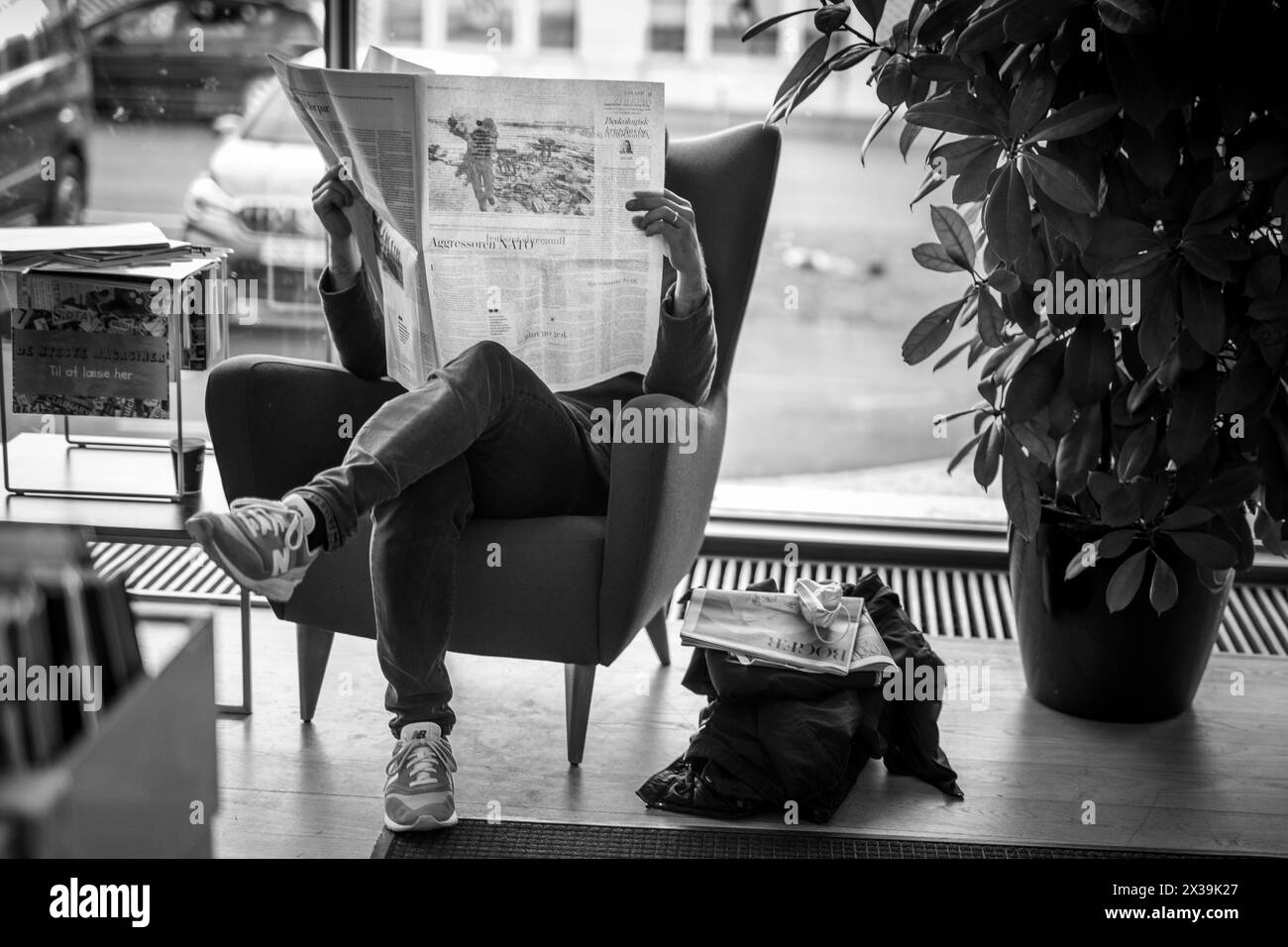 Man reading paper in designerchair Stock Photo - Alamy