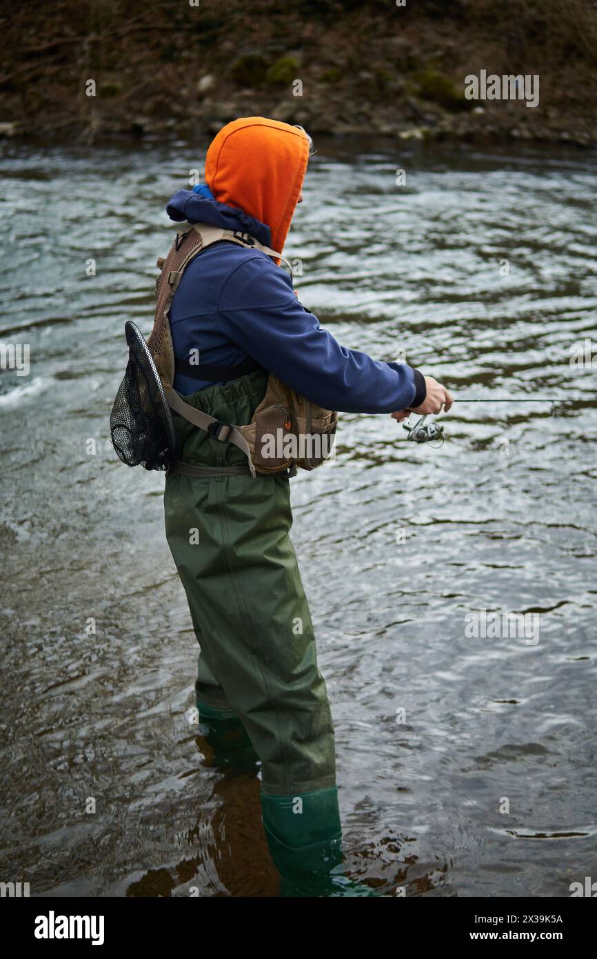 Fisherman fishing by the river in daytime with tackle bag and net Stock ...