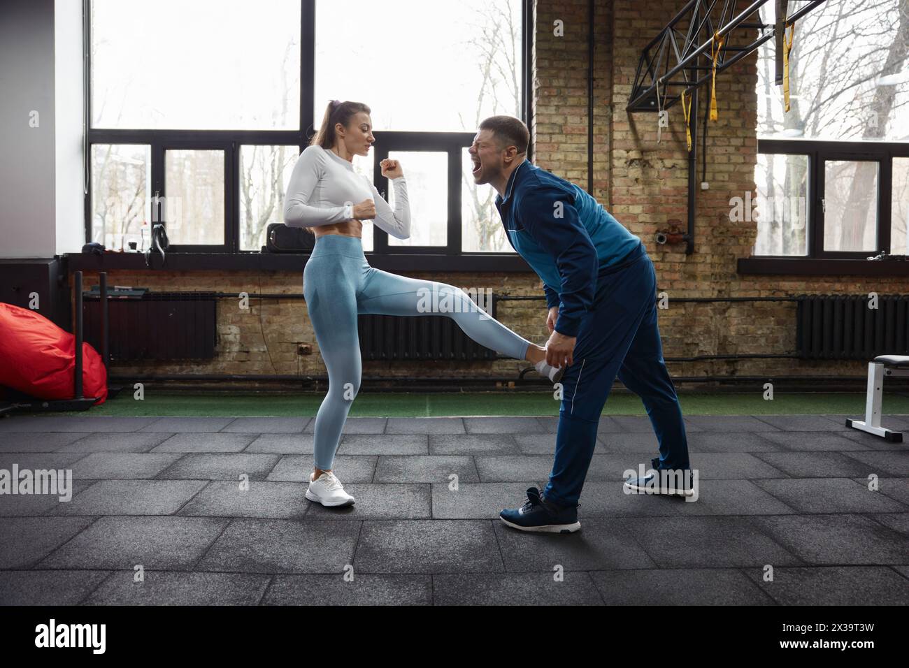 Young skilled woman practicing kicks during mma lesson with instructor ...