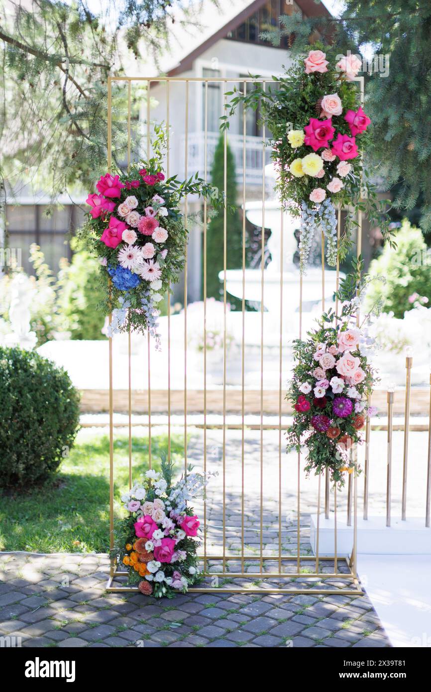 Two vibrant flowers are blooming from the metal bars of a gate, adding ...