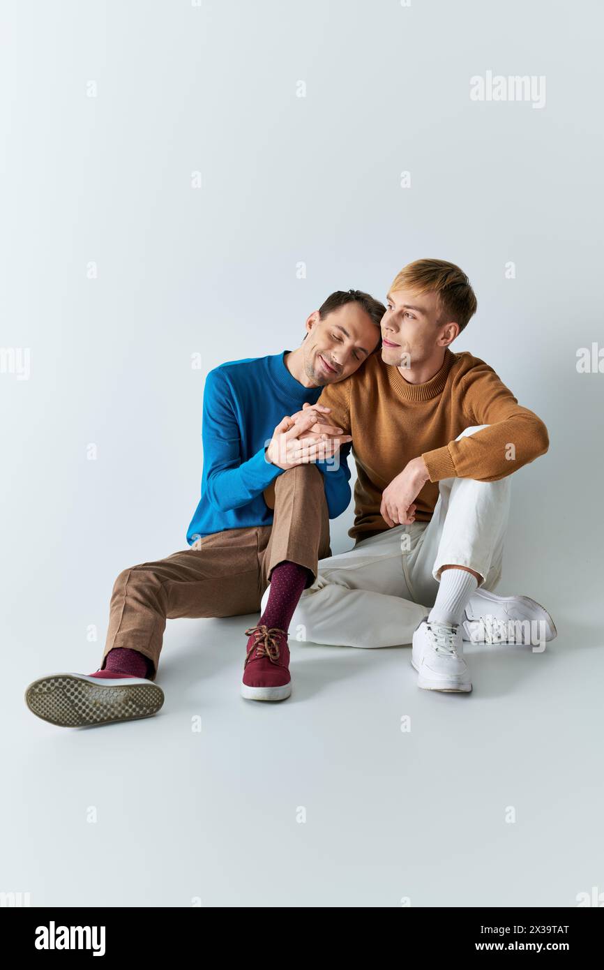 Two men, a loving gay couple, sitting next to each other in casual ...