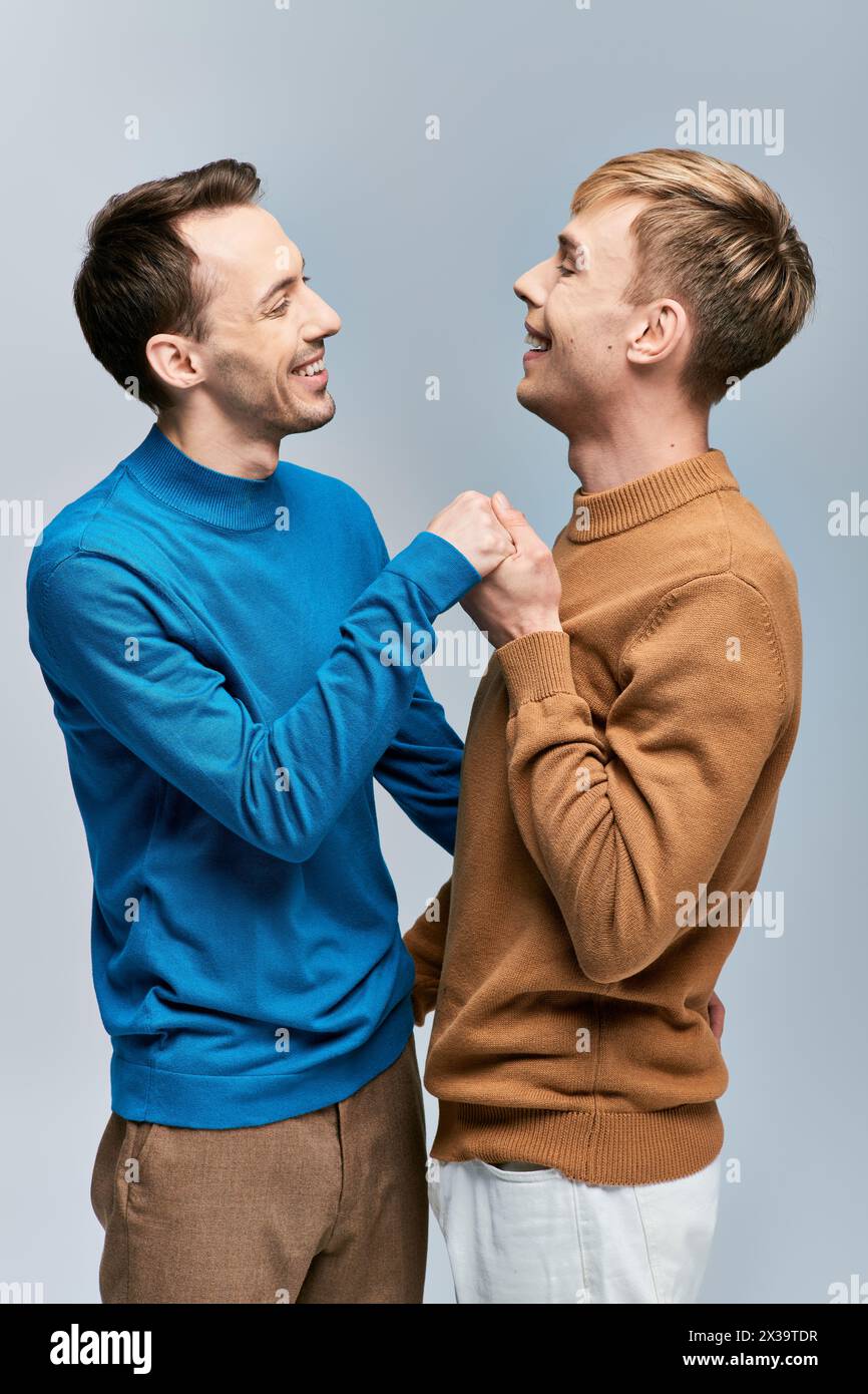 Two men in casual attire stand side by side holding hands Stock Photo ...