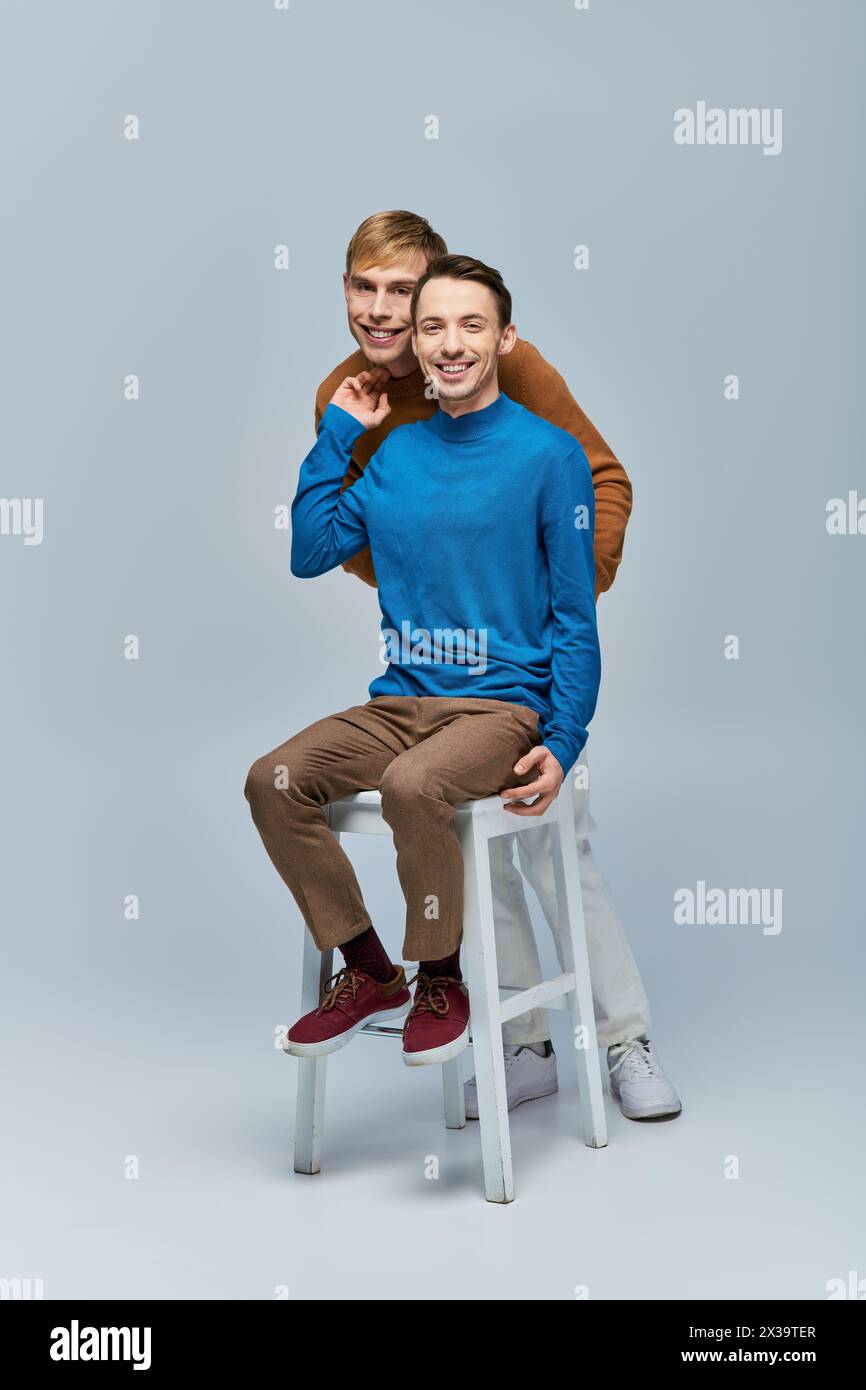 Two men in casual attire striking a pose on a gray backdrop Stock Photo ...