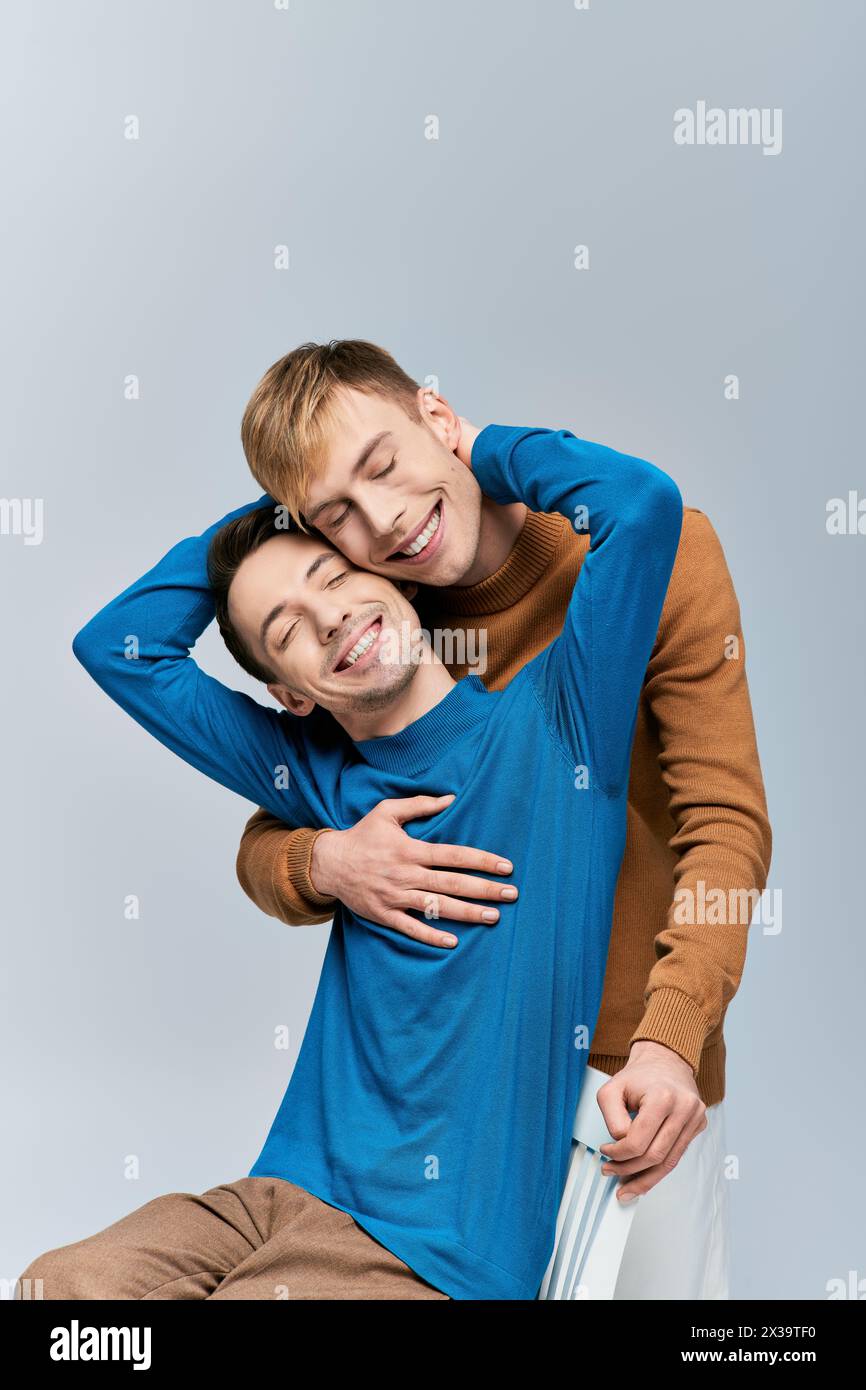 Two men in casual attire hugging on a chair Stock Photo - Alamy