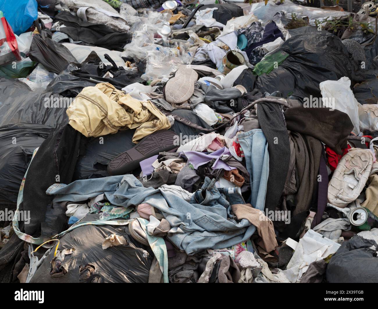 Close-up of pile of discarded clothes and other waste dumped at side of ...