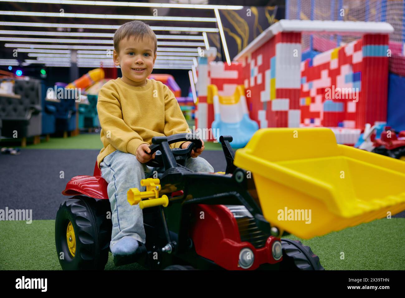 Little boy preschooler riding toy tractor at indoor playground Stock ...