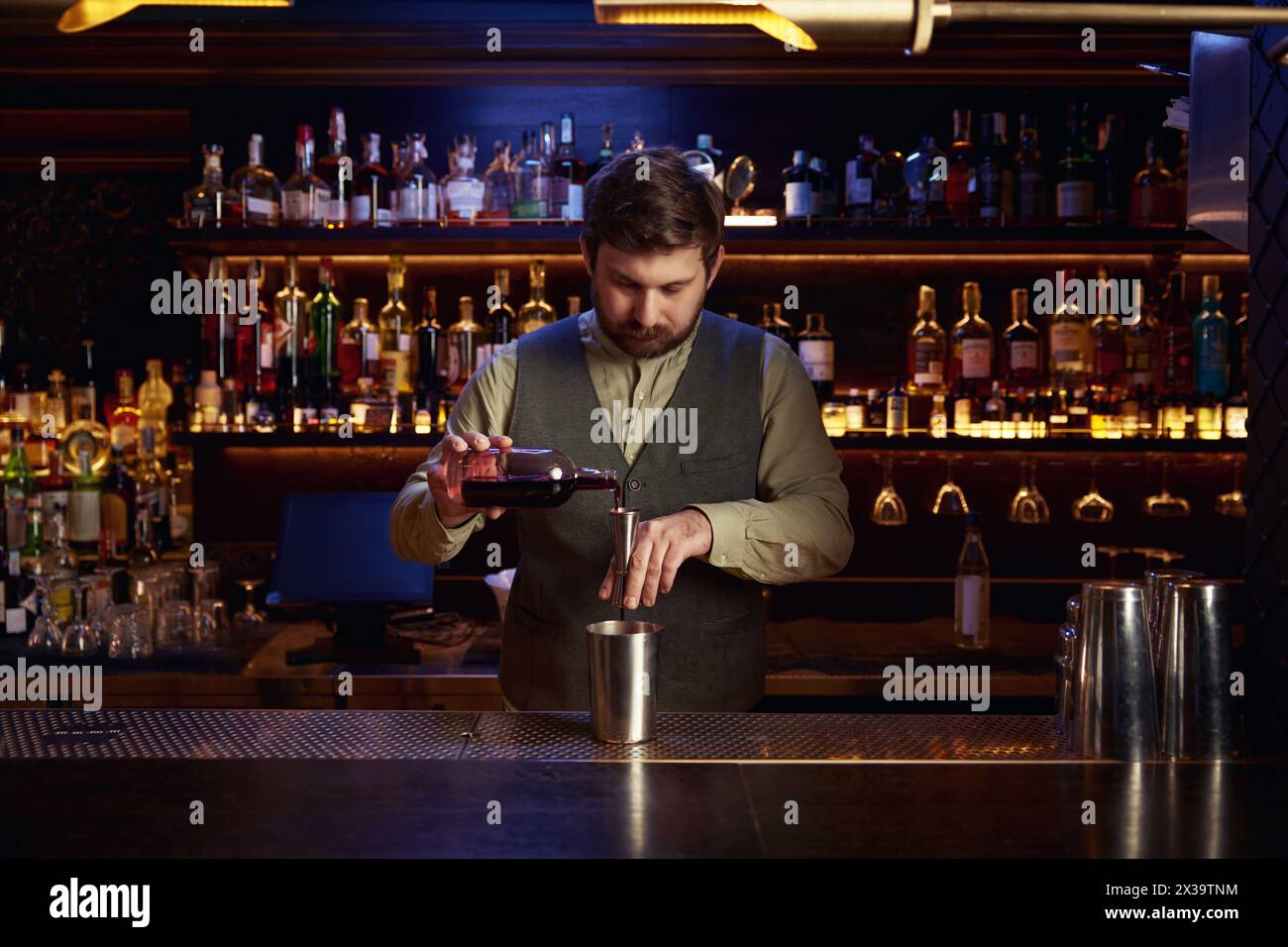Bartender in uniform pouring drink into shaker behind bar Stock Photo ...