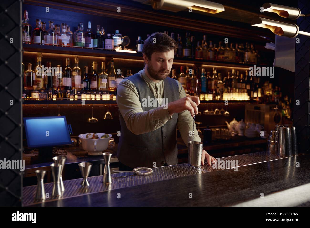 Professional bartender mixing cocktail ingredients standing at ...
