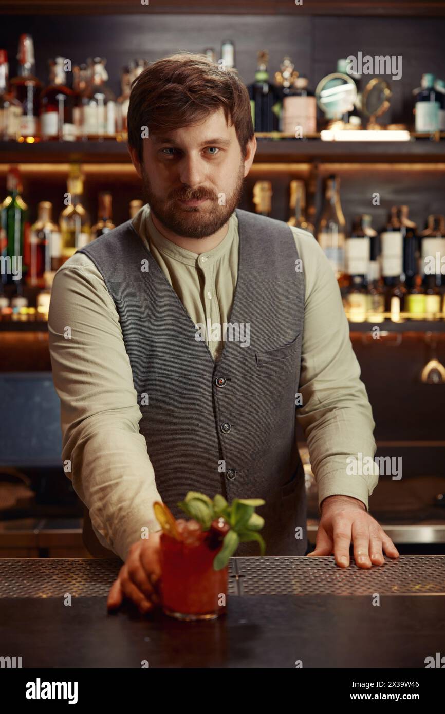 Portrait of bartender giving cocktail to client of nightclub or hotel ...