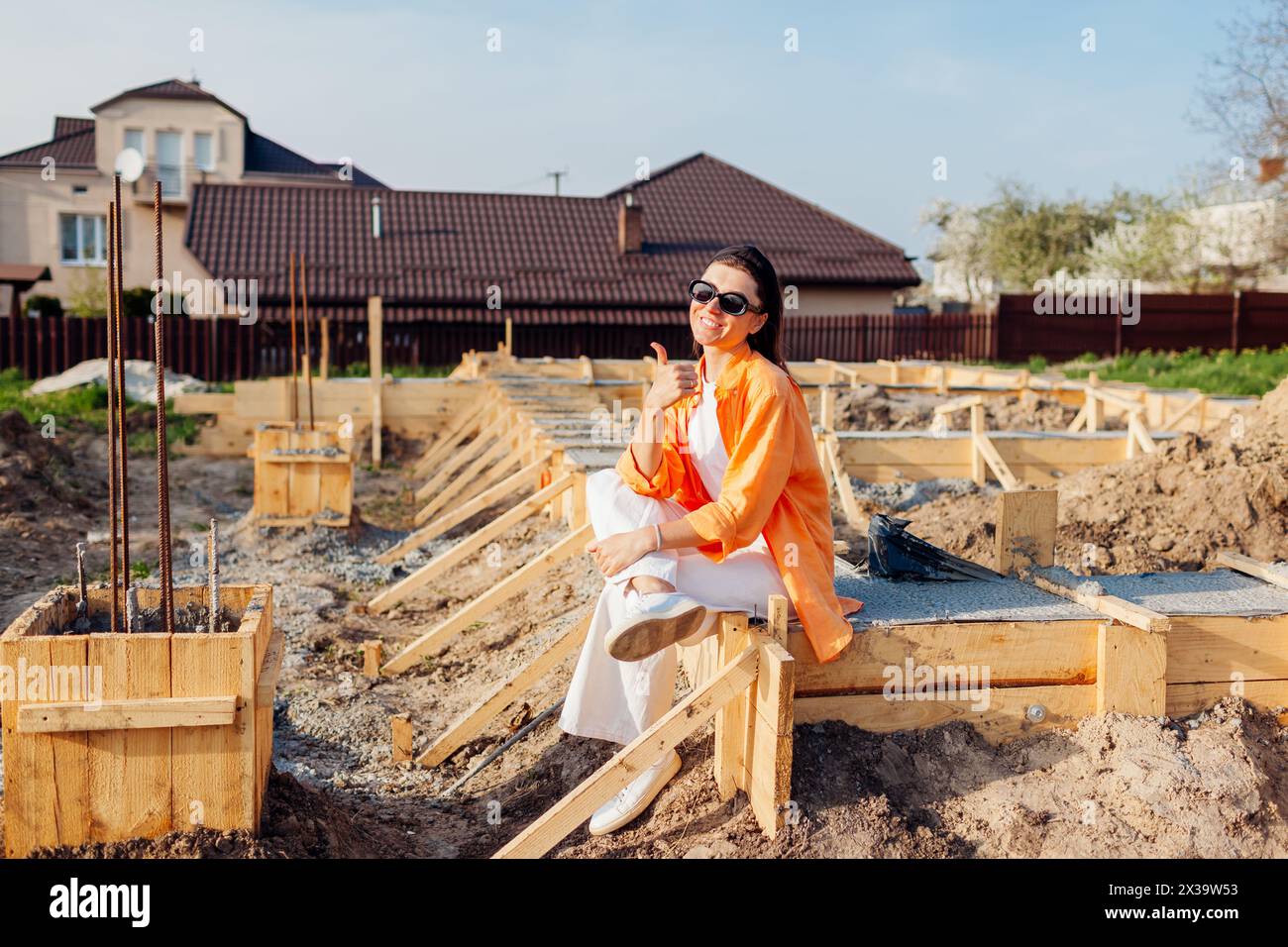 Happy woman owner sitting on concrete foundation for new house ...