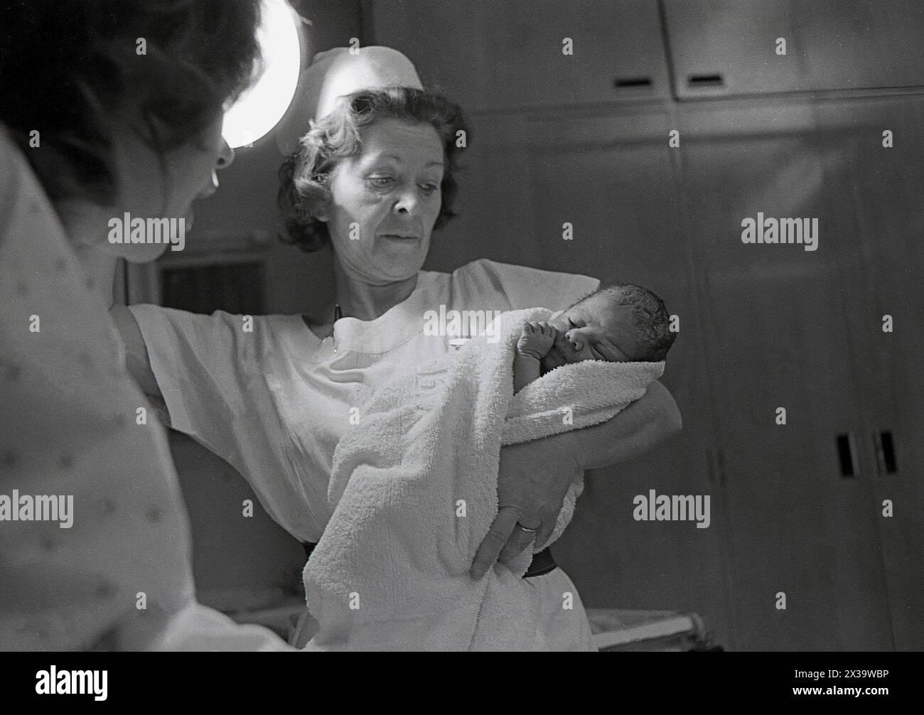 1970s, historical, a new baby wrapped in a towel being held by ...