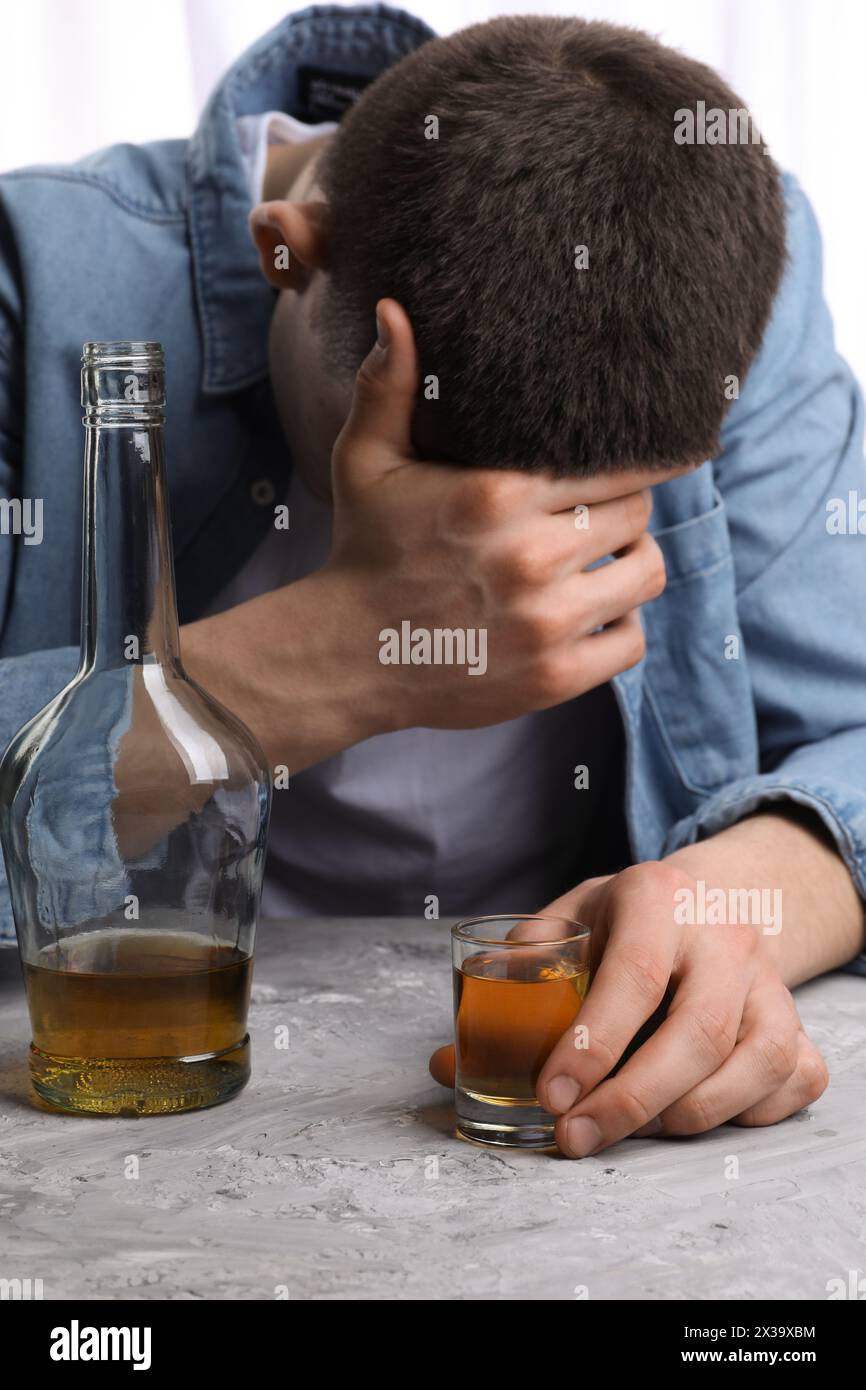 Alcohol addiction. Man with whiskey at grey textured table Stock Photo ...