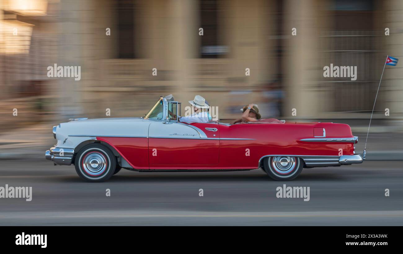 Classic car being driven along the sea front on the Malecon in front of ...
