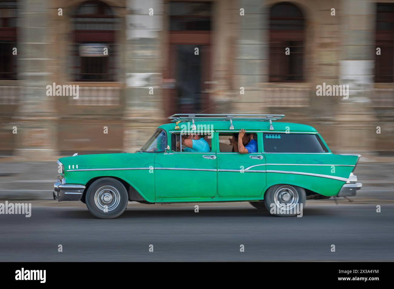 Classic car being driven along the sea front on the Malecon in front of ...