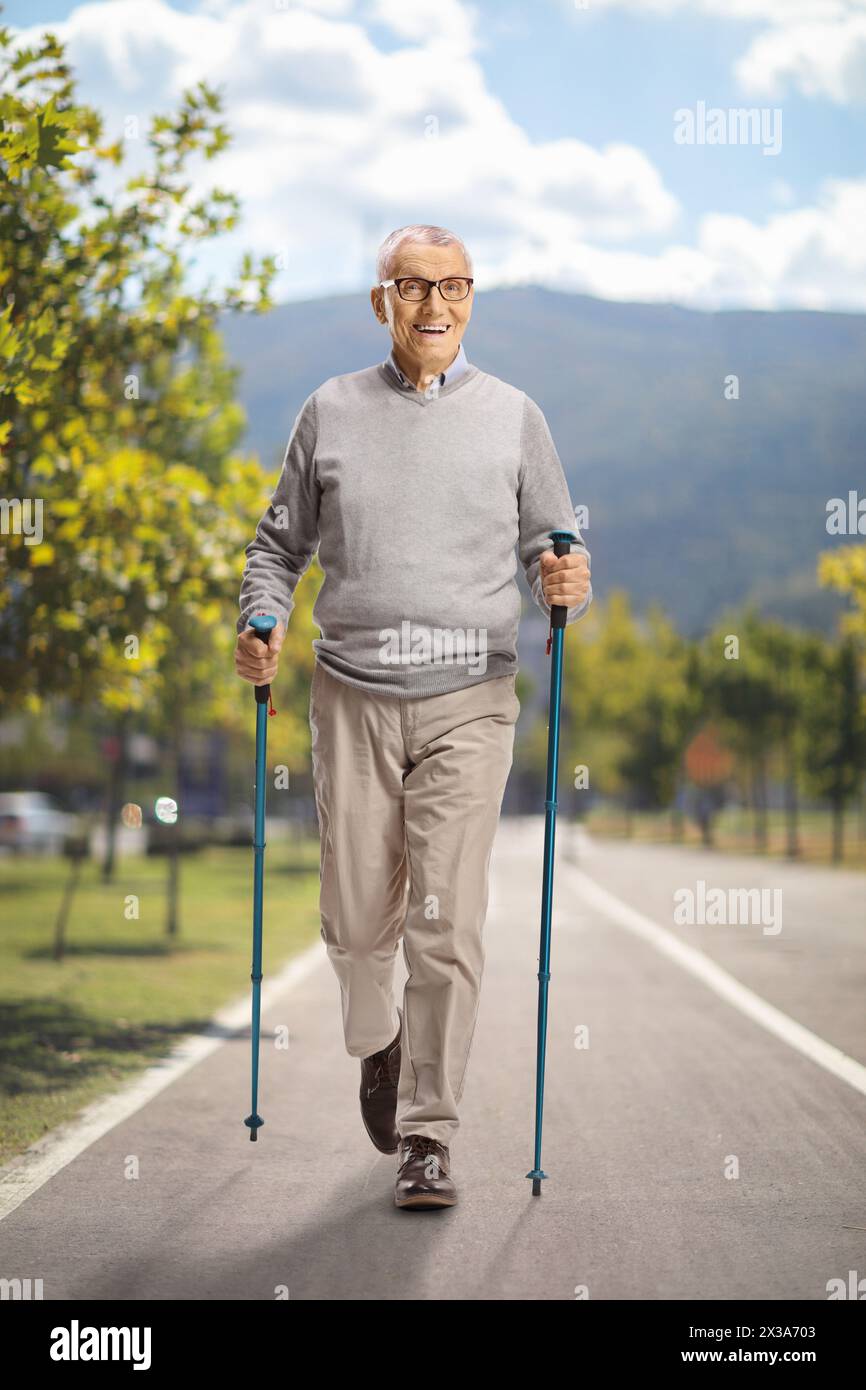 Elderly man walking with poles in a park Stock Photo - Alamy
