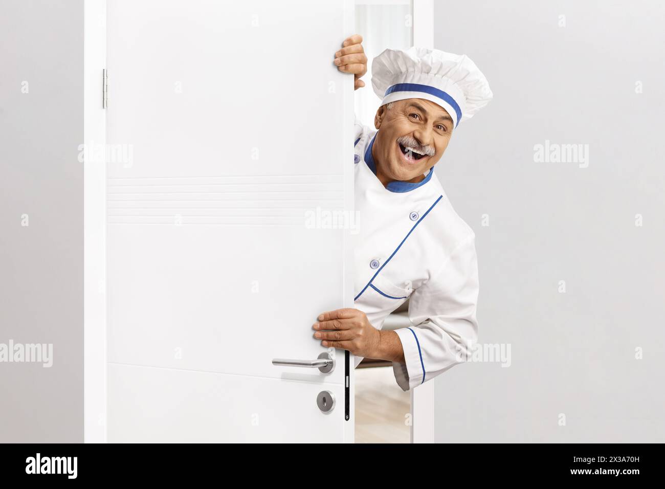 Mature male chef in a uniform opening a door and smiling Stock Photo ...
