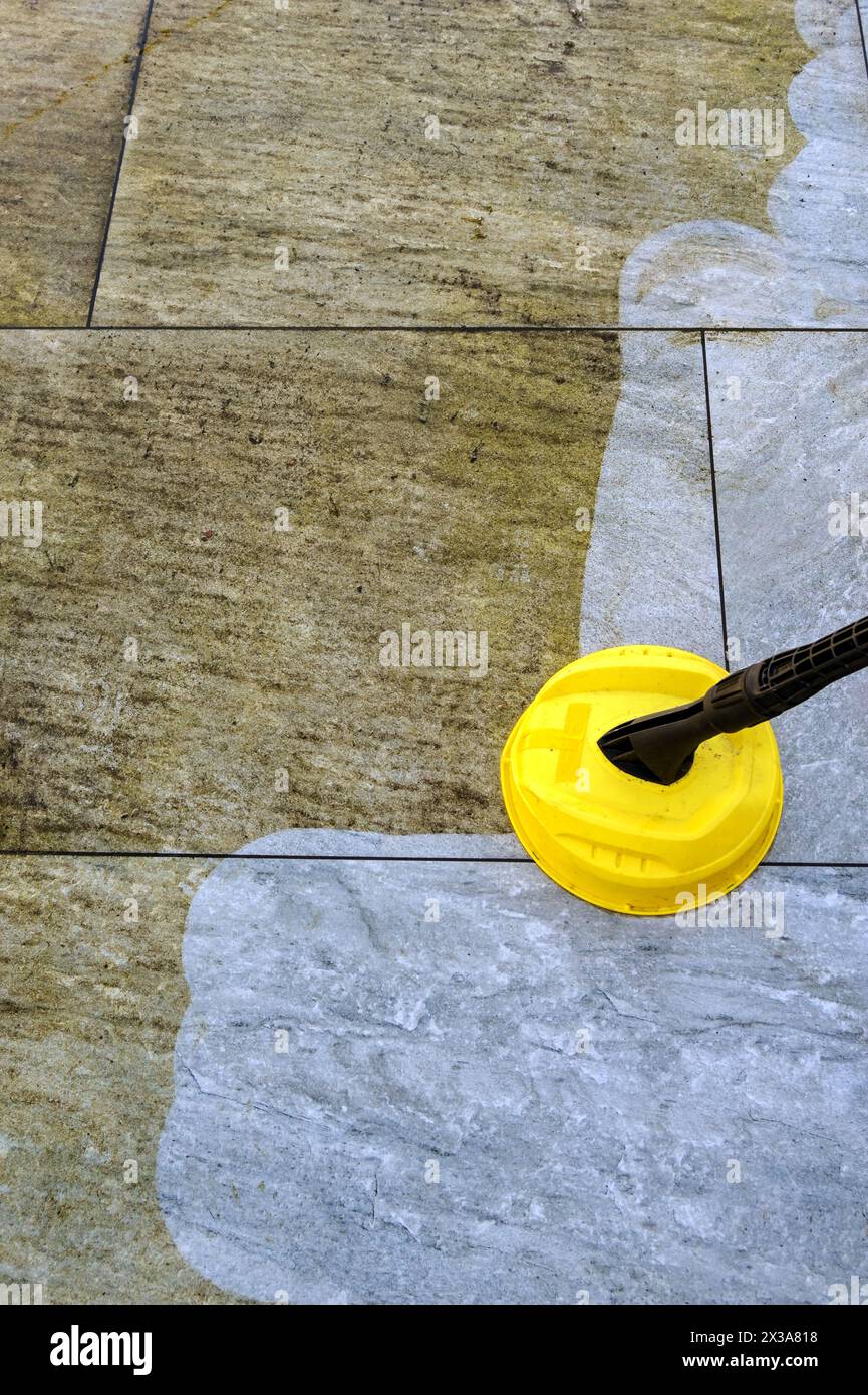 Pressure jet washer being used to clean porcelain tiles on a garden ...