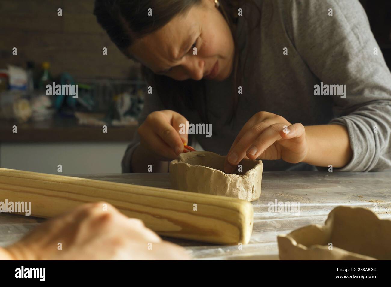 The woman shapes the product and cuts off excess clay from the walls of ...