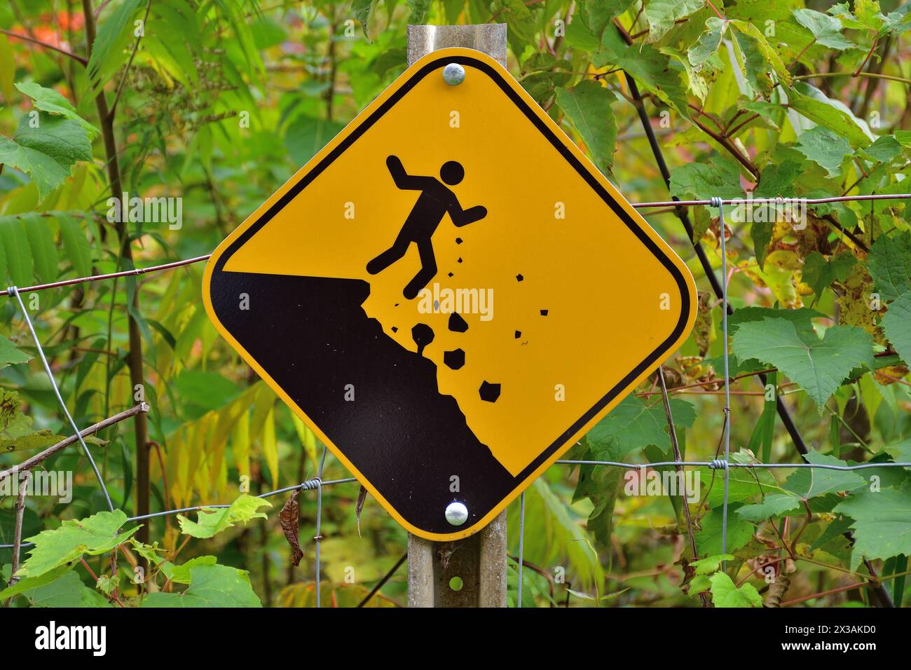 Safety sign black and yellow falling from a cliff Stock Photo - Alamy