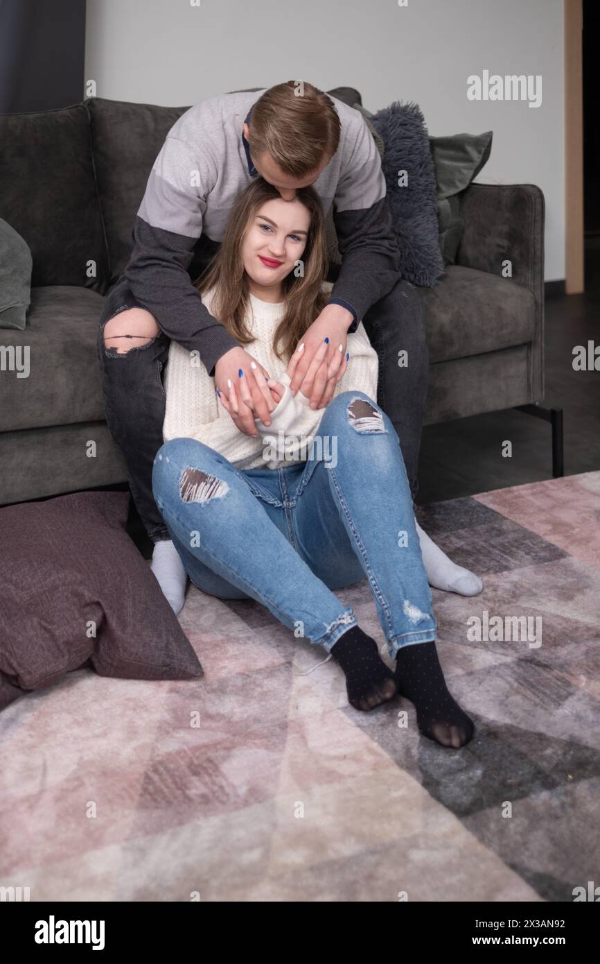 A couple seated closely on a couch shares a comforting embrace, their ...
