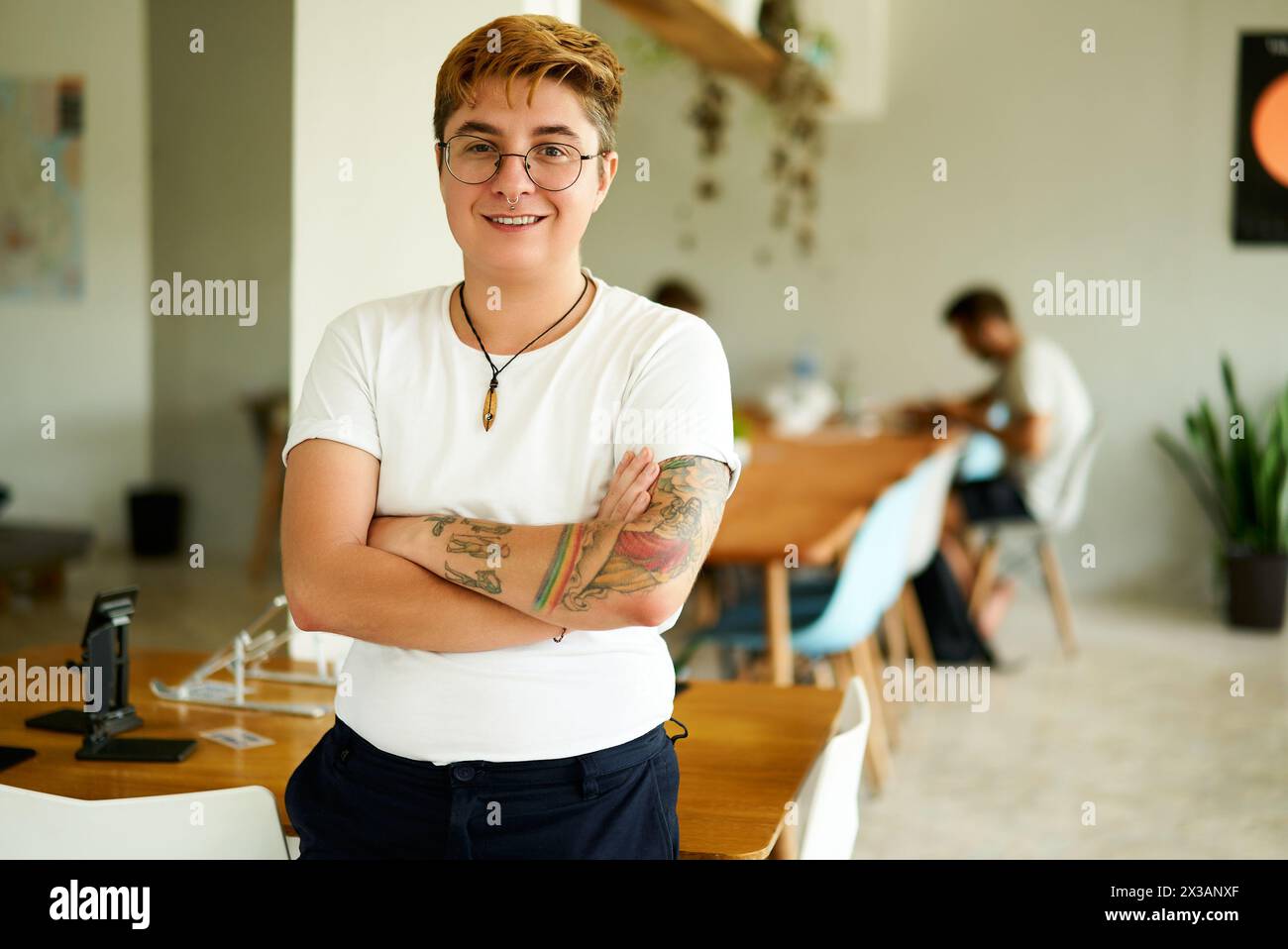 Confident transgender male with tattoos stands in a modern office ...