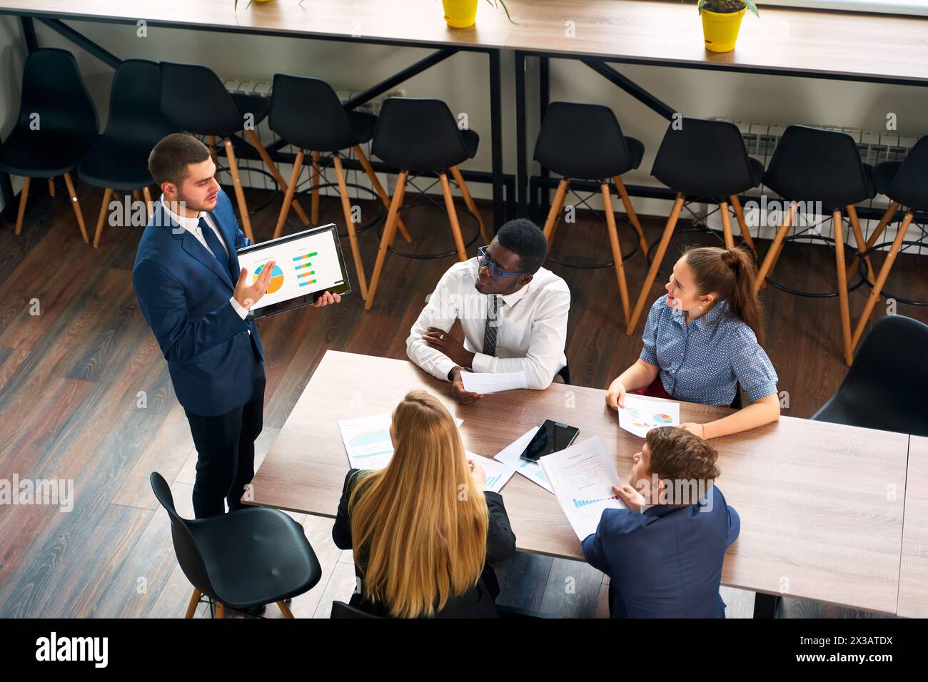 Arabic executive presents growth chart on tablet to diverse colleagues at office boardroom ...