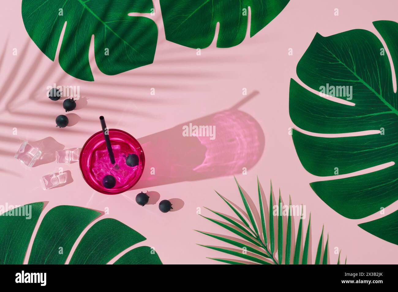 Summer scene made with cold pink refreshing drink and green tropical ...