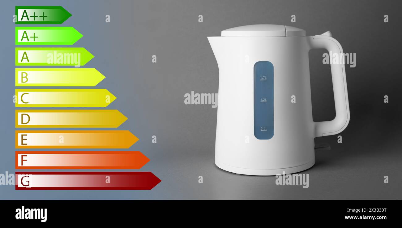 Energy efficiency rating label and electric kettle on grey background ...