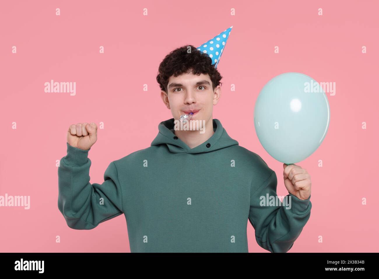 Young man in party hat with blower and balloon on pink background Stock ...