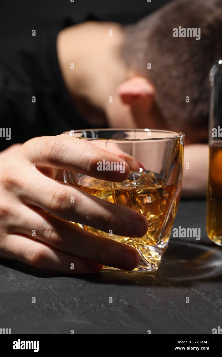 Alcohol addiction. Man with glass of whiskey at dark textured table ...