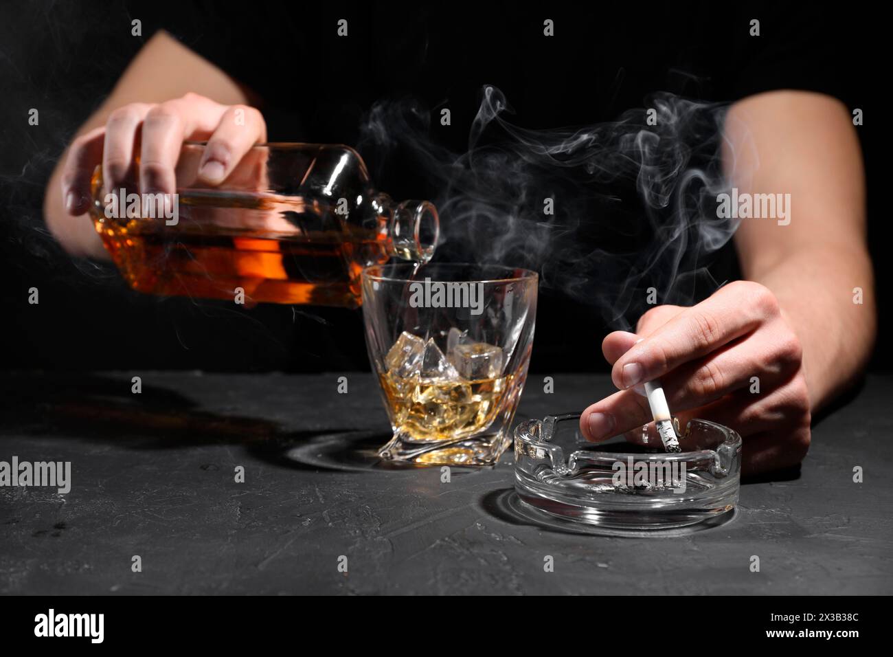 Alcohol addiction. Man with smoldering cigarette pouring whiskey into ...