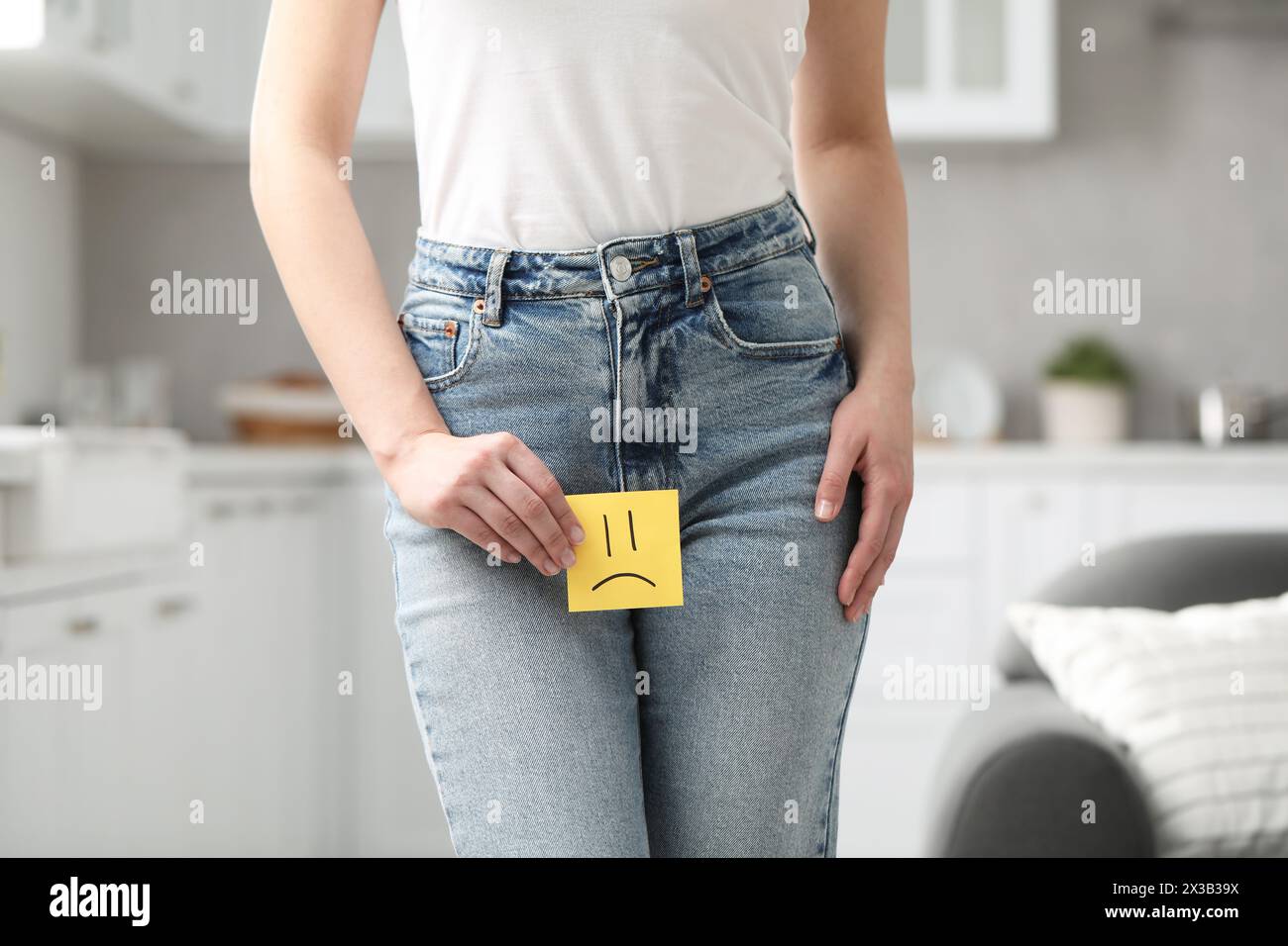 Cystitis. Woman holding sticky note with drawn sad face at home ...