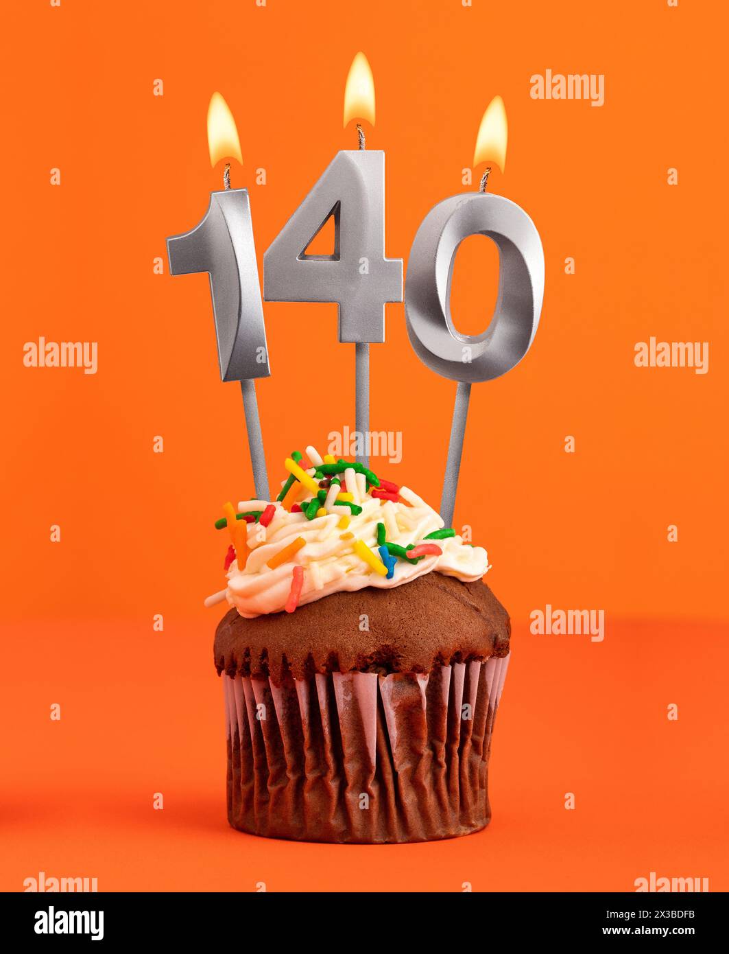 Birthday cupcake with number 140 candle - Orange color background Stock Photo - Alamy