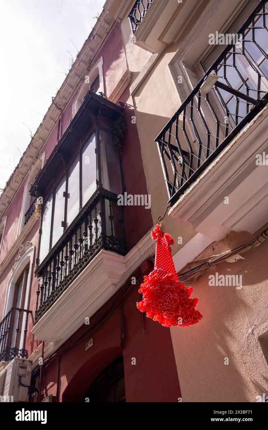 A traditional red flamenco dress hung on a balcony with black iron ...
