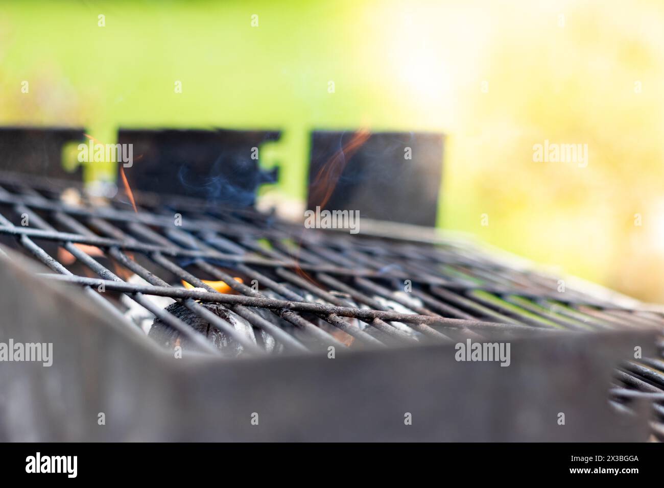 Close up view of an empty grill with wood underneath burning and fire ...