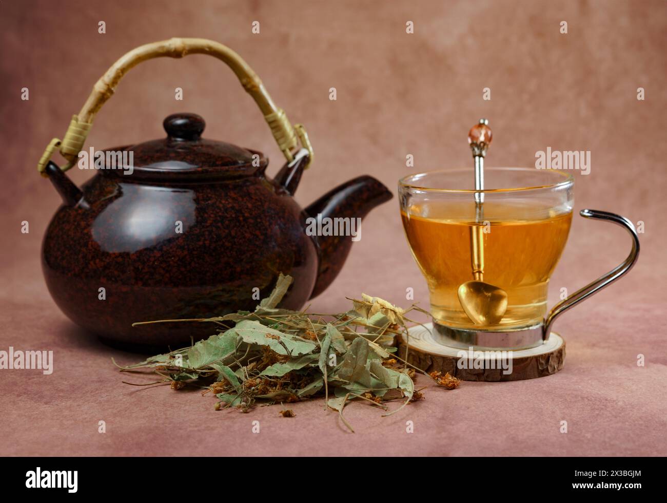 Glass cup with teapot and fresh linden leaves, infusion of lime blossom ...