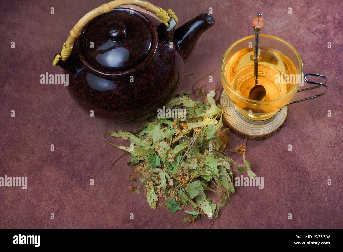 Top view of glass cup with teapot and fresh linden leaves, infusion of ...