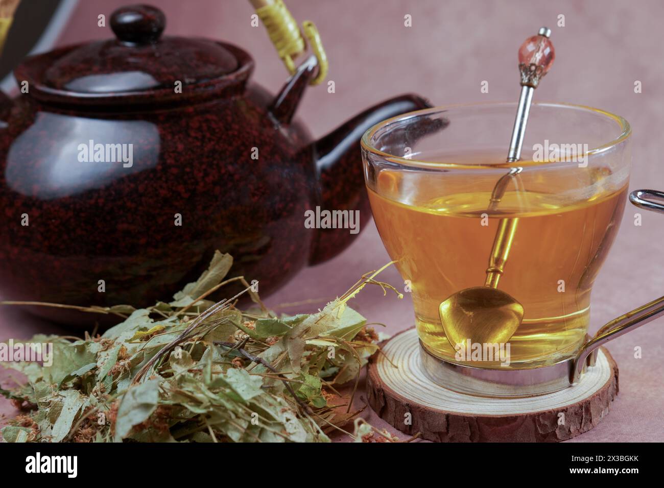 Glass cup with teapot and fresh linden leaves, infusion of lime blossom ...